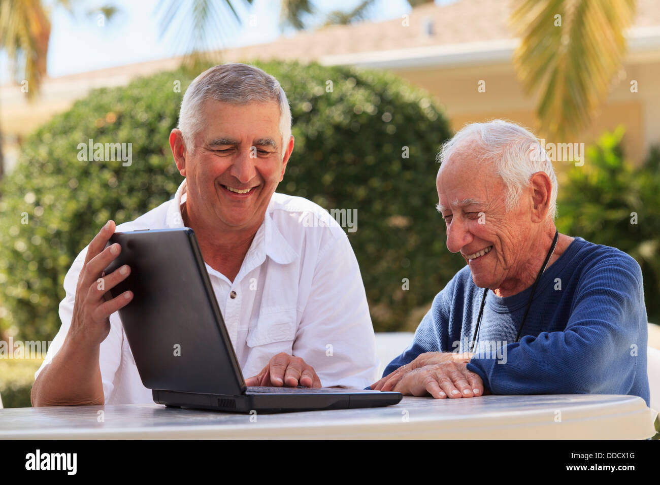 Elderly man using a laptop with his son beside him Stock Photo - Alamy