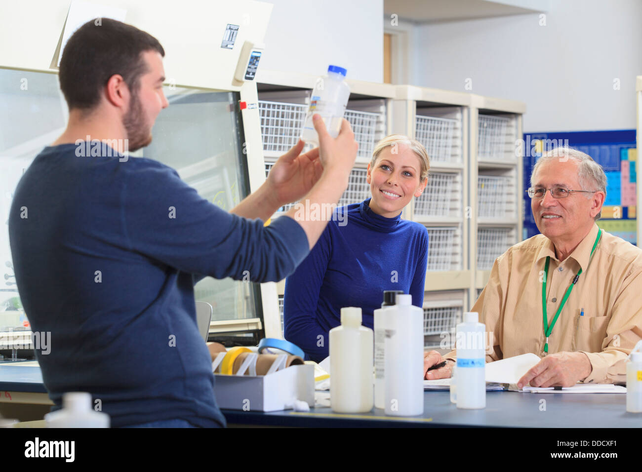 Engineering professor discussing chemical reagents with students in a ...