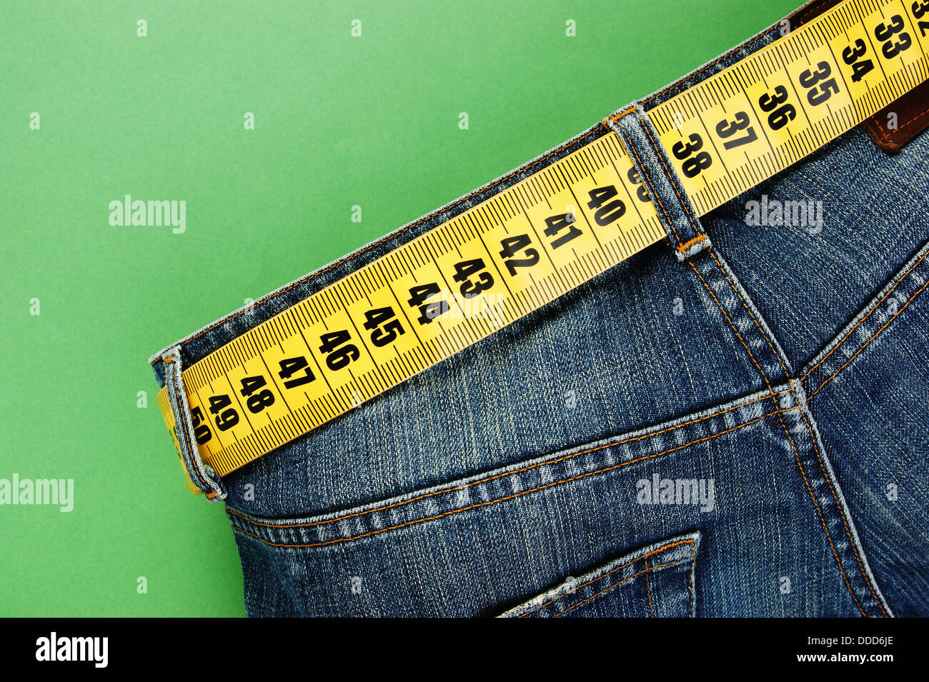 jeans with meter belt slimming on the green background Stock Photo - Alamy