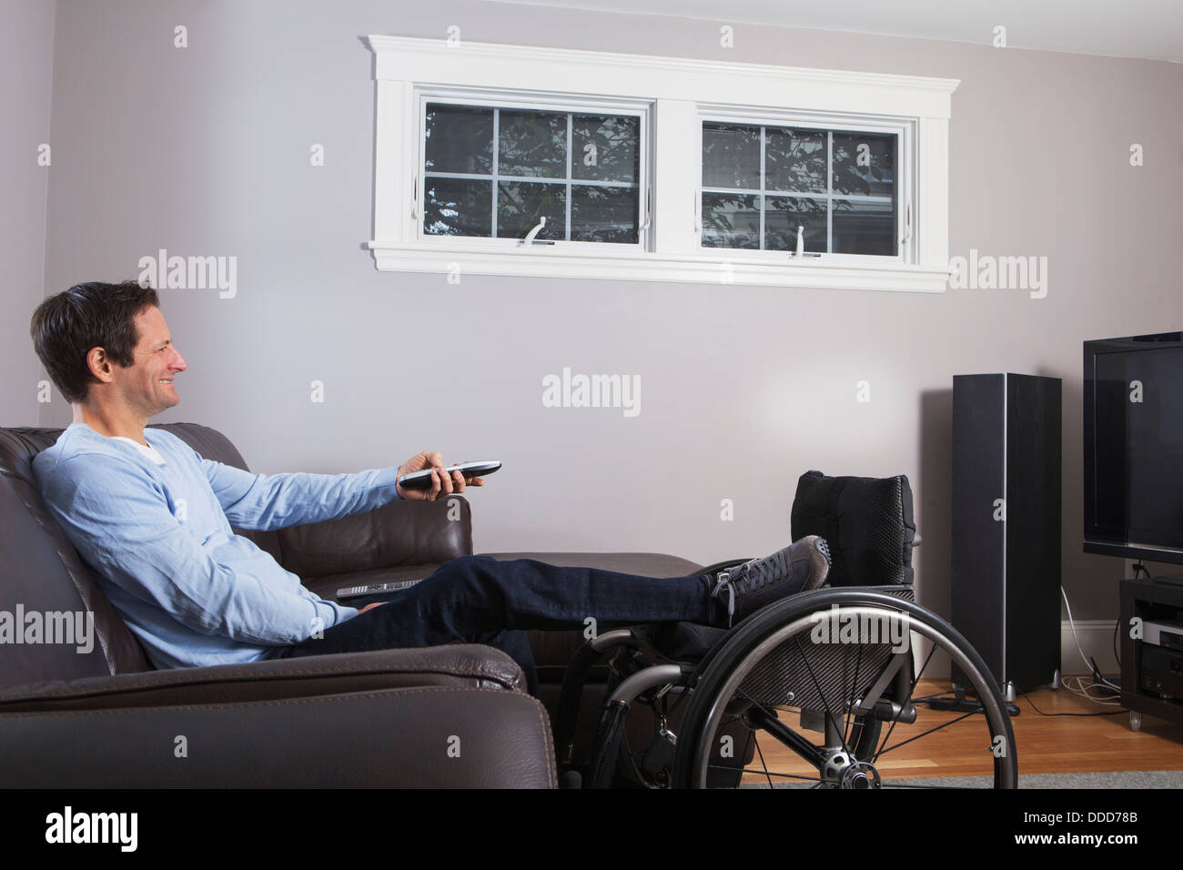 Man with spinal cord injury with leg in wheelchair watching TV with ...