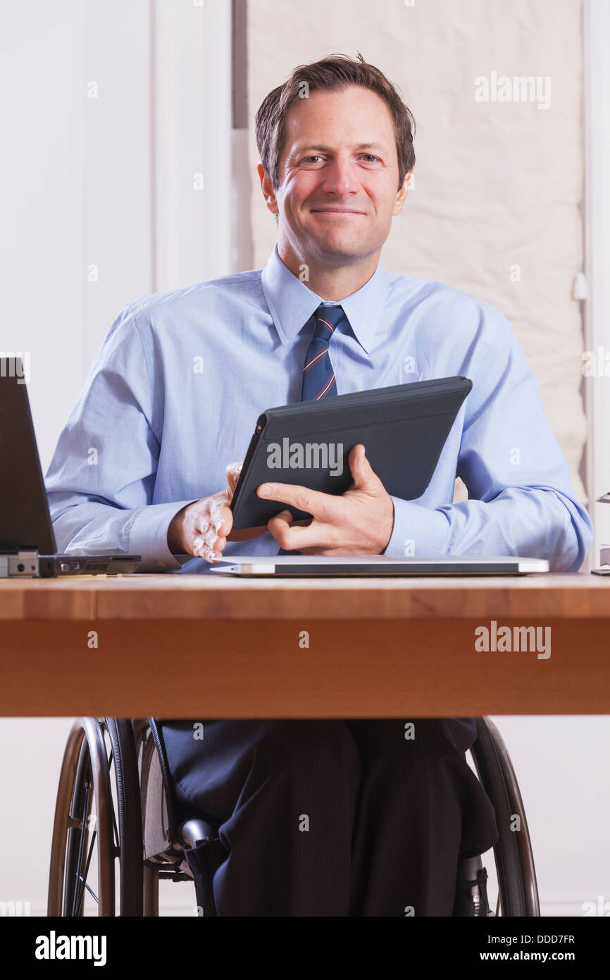 Businessman with spinal cord injury in a wheelchair using a tablet ...