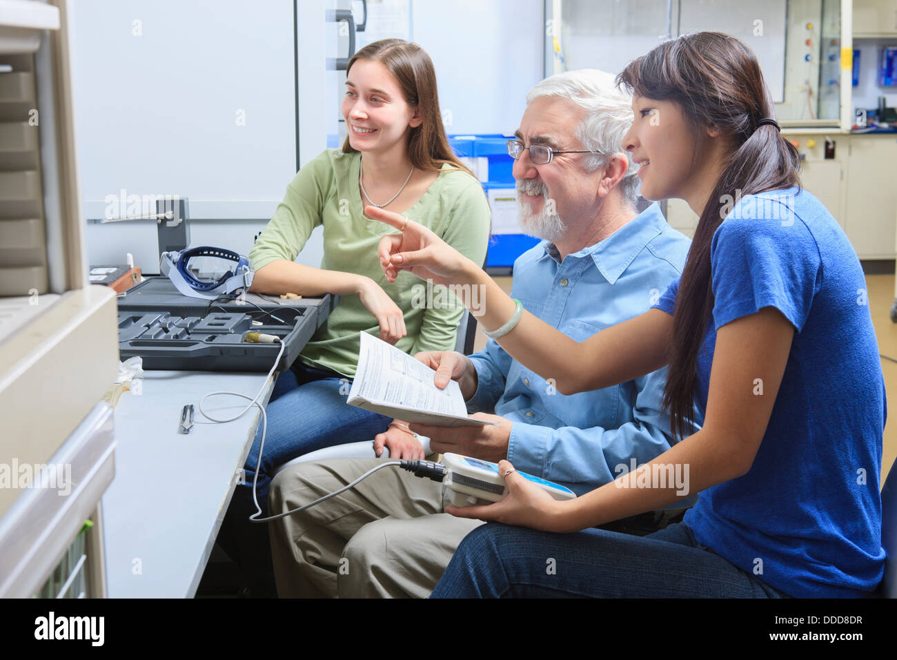 Professor working with students in a chemistry lab learning about ...
