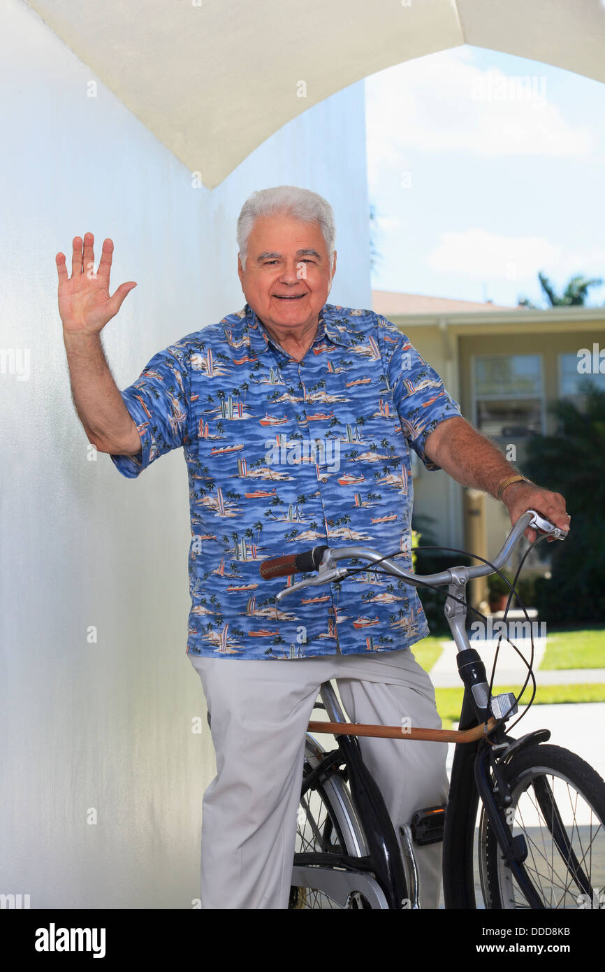 Senior man with polio waving his hand on bicycle with cane attached ...