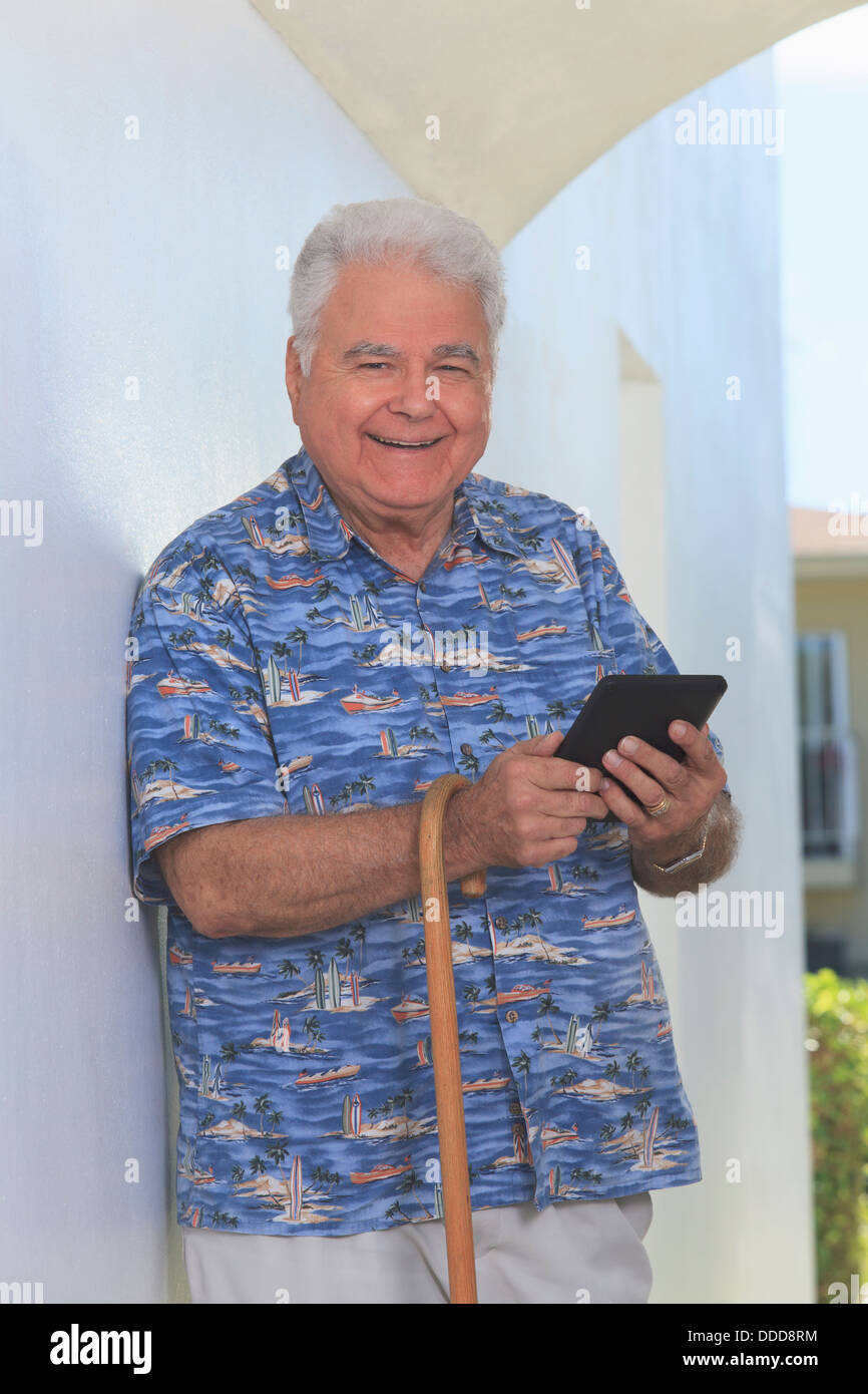Senior man with polio using a digital tablet while holding his cane ...