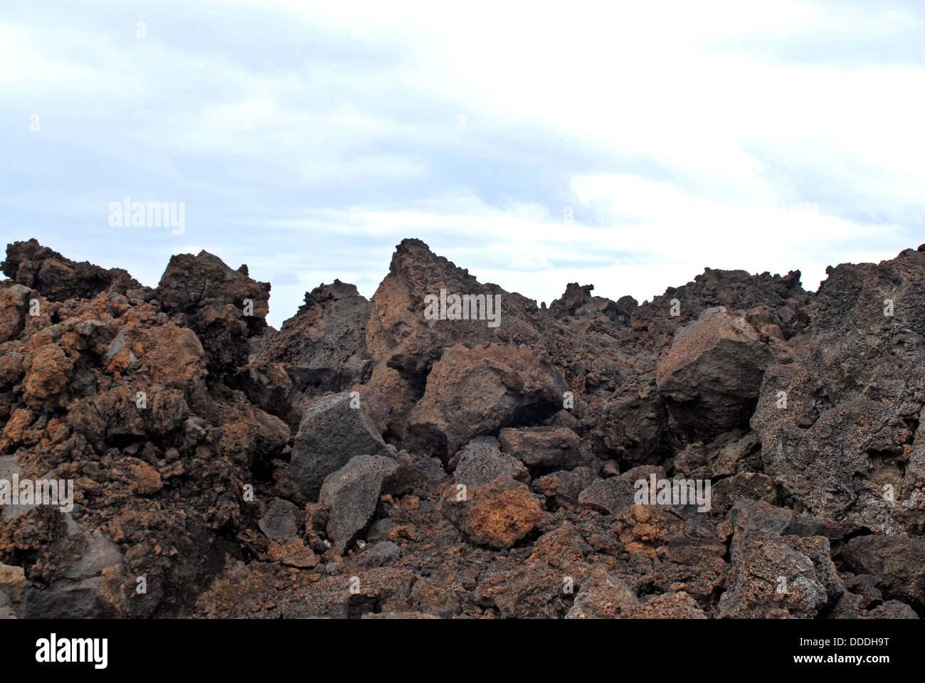 Jagged volcanic basalt rocks against overcast sky Stock Photo - Alamy