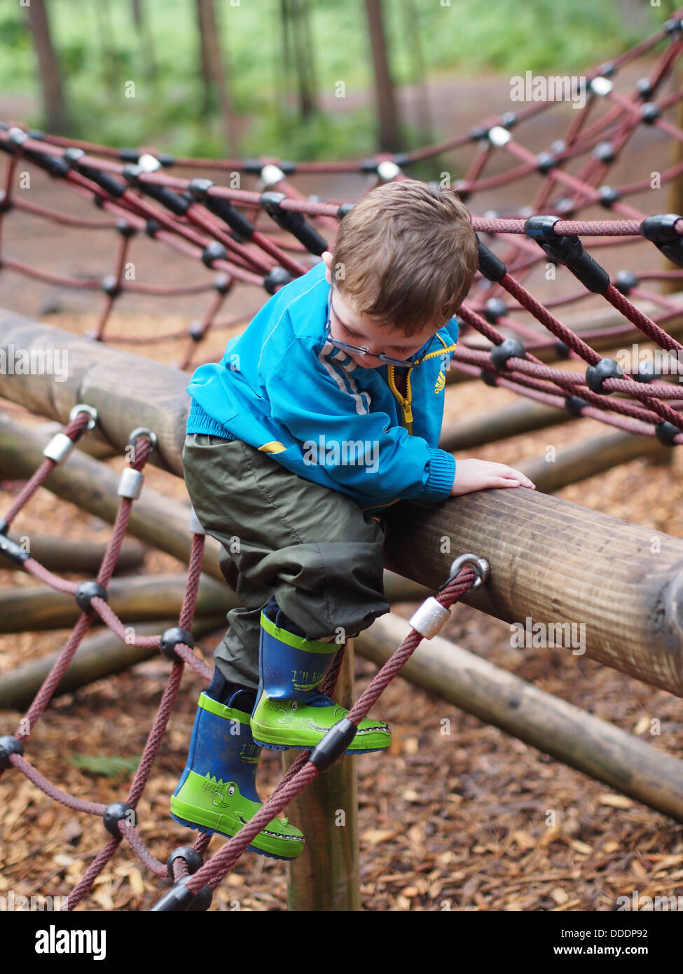 A young boy in an adventure playground climbs netting Stock Photo - Alamy