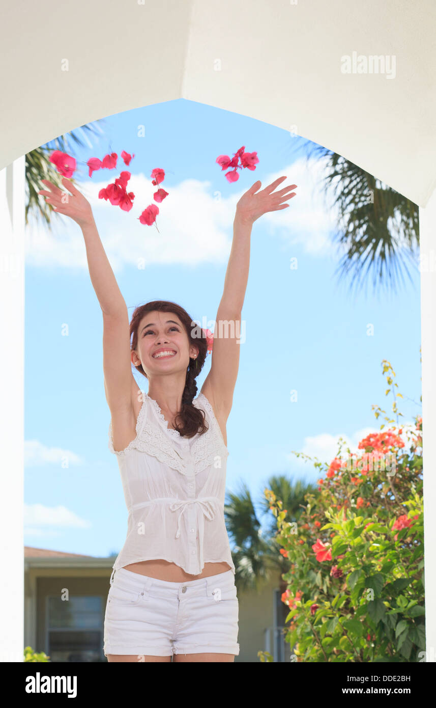 Smiling young woman throwing flower petals in the air Stock Photo - Alamy