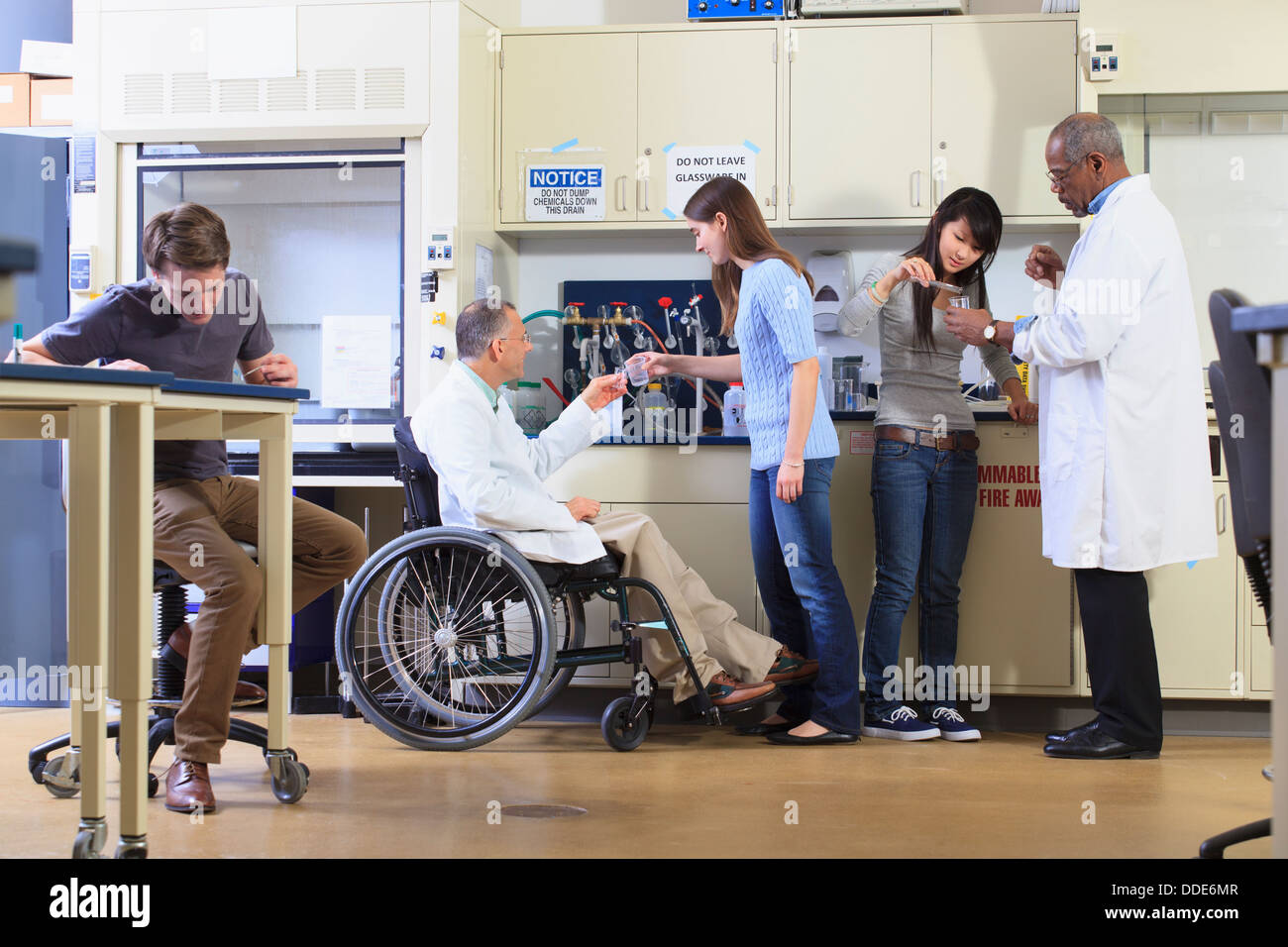 Two professors working with students in an engineering lab working on ...