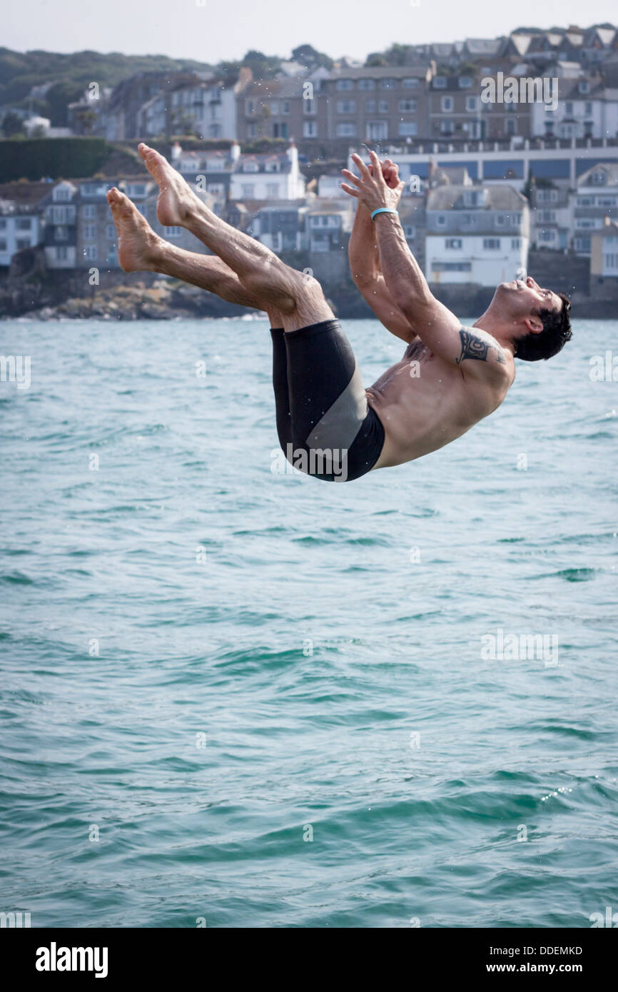 A man diving off a home made diving board into the quay at St. Ives ...