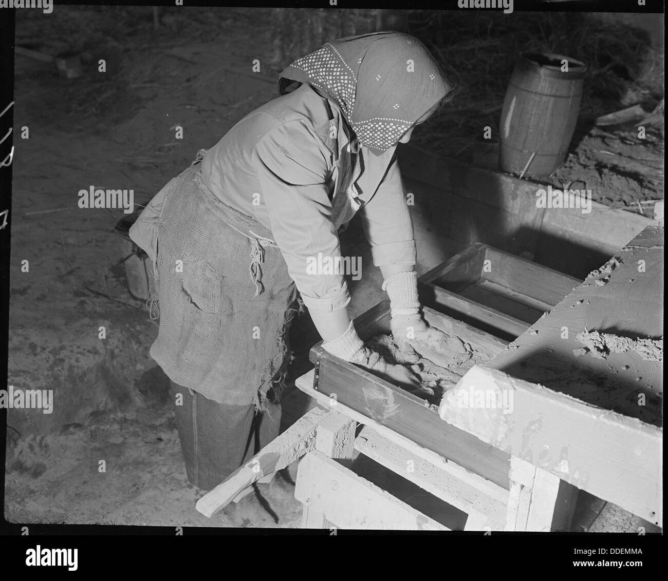 The photograph shows a woman working at an adobe factory in Poston ...