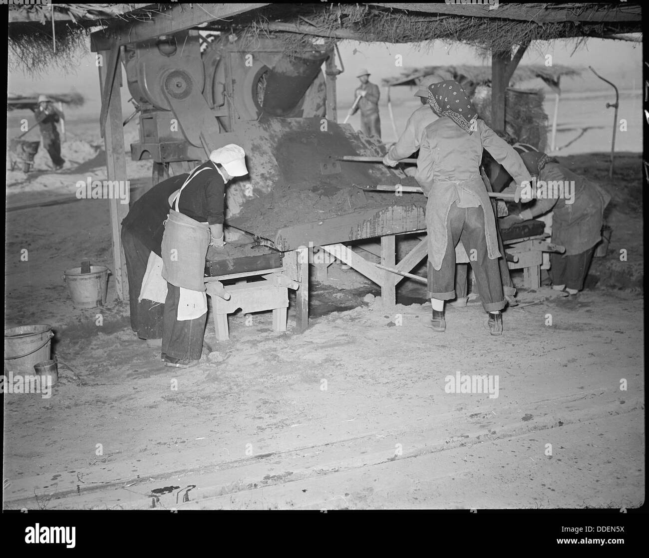 Women workers are seen scraping mortar into adobe frames at an adobe ...