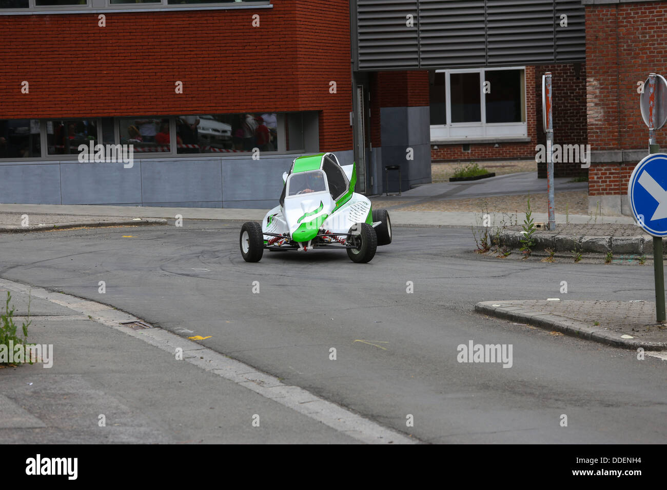 White and green racing buggy taking a curve on 3 wheels on asphalt ...