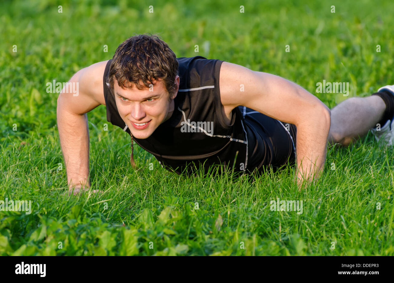 Handsome smiling man doing push-ups at the park Stock Photo - Alamy