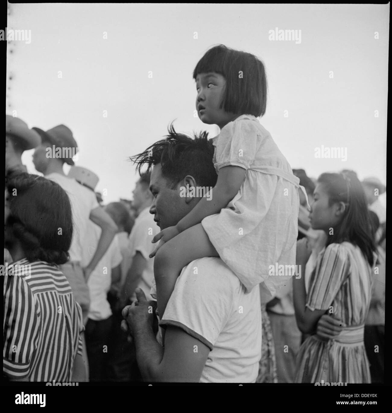 In Poston, Arizona, a young evacuee of Japanese descent is carried on ...