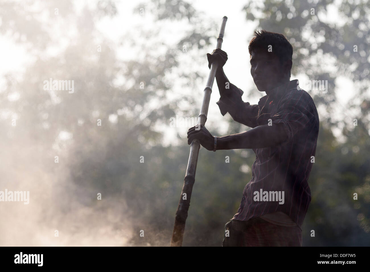 A manual worker tends a fire heating tar to lay on the road by hand in ...