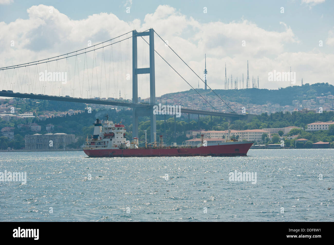 Large cargo ship traveling under a suspension bridge on bosphorus river ...