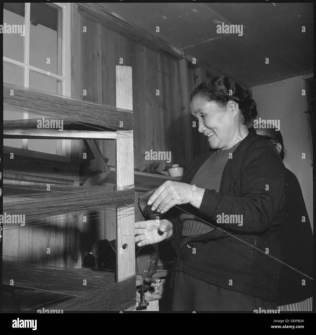 An Issei woman is seen winding yarn in the weaving room at the Rohwer ...