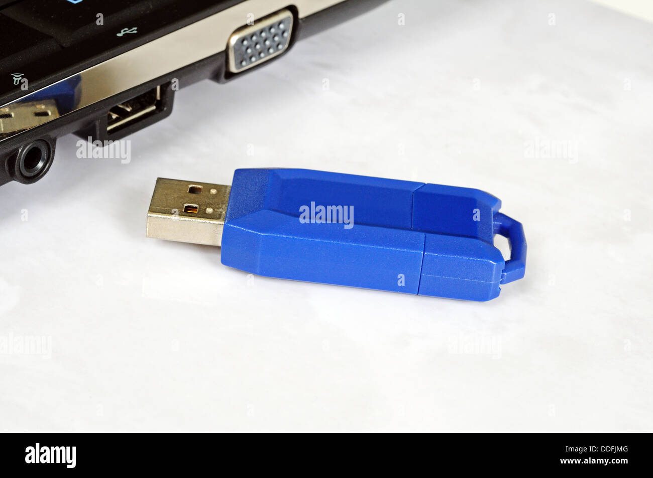 Blue USB stick sitting alongside a netbook against a white background ...