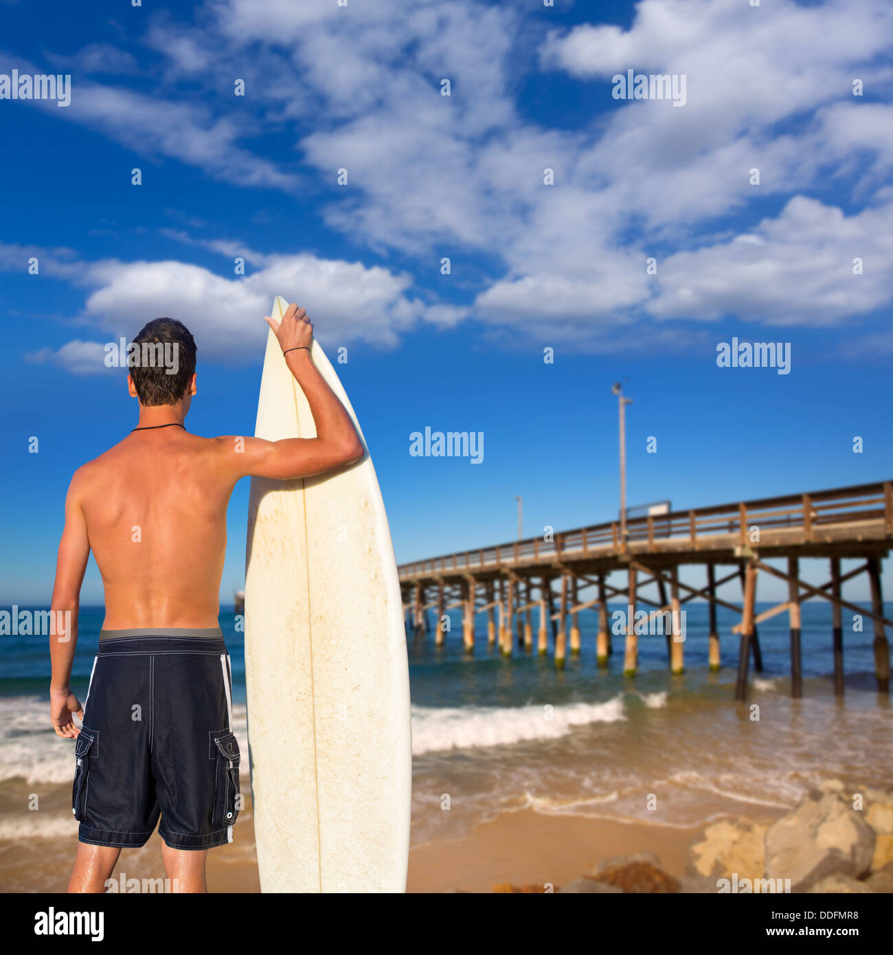 Boy surfer back rear view holding surfboard on Newport pier beach ...
