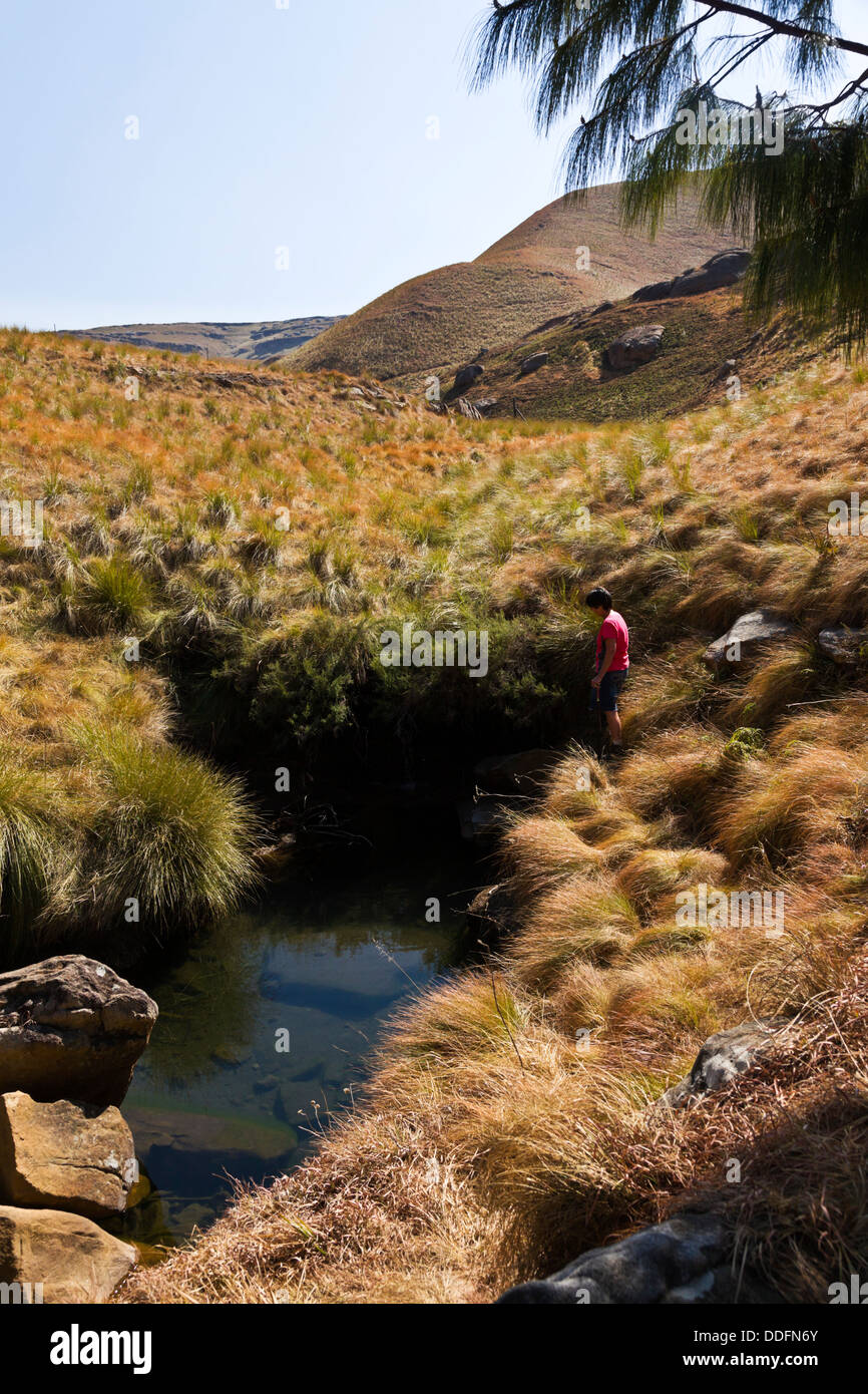 A female hiker stands next to a mountain spring discovered during her ...