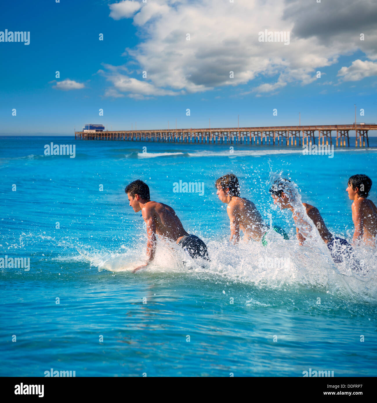 Teenager surfers surfing running jumping on surfboards at Newport pier ...