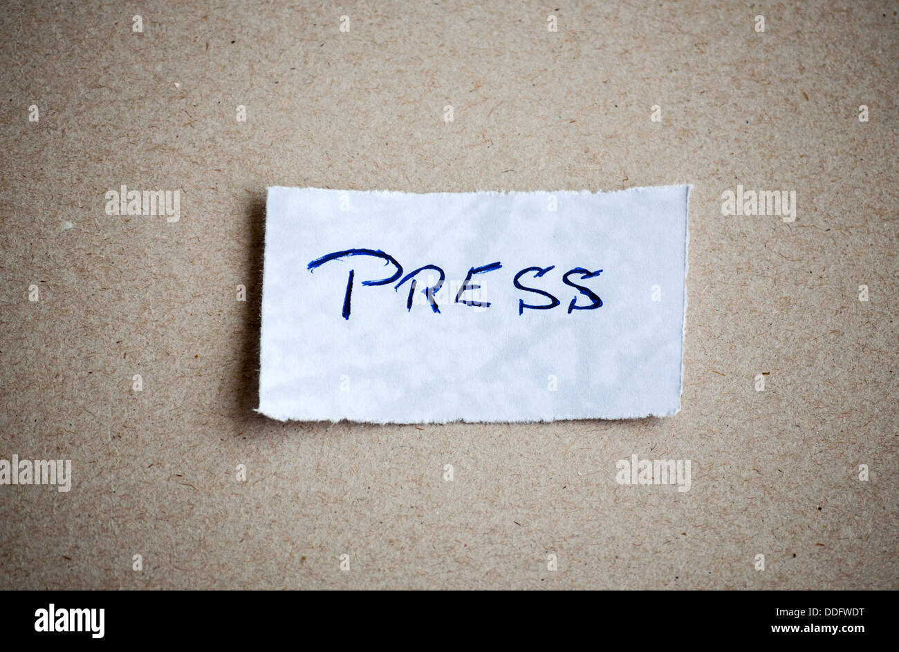 Press message,written on piece of paper, on cardboard background. Space ...
