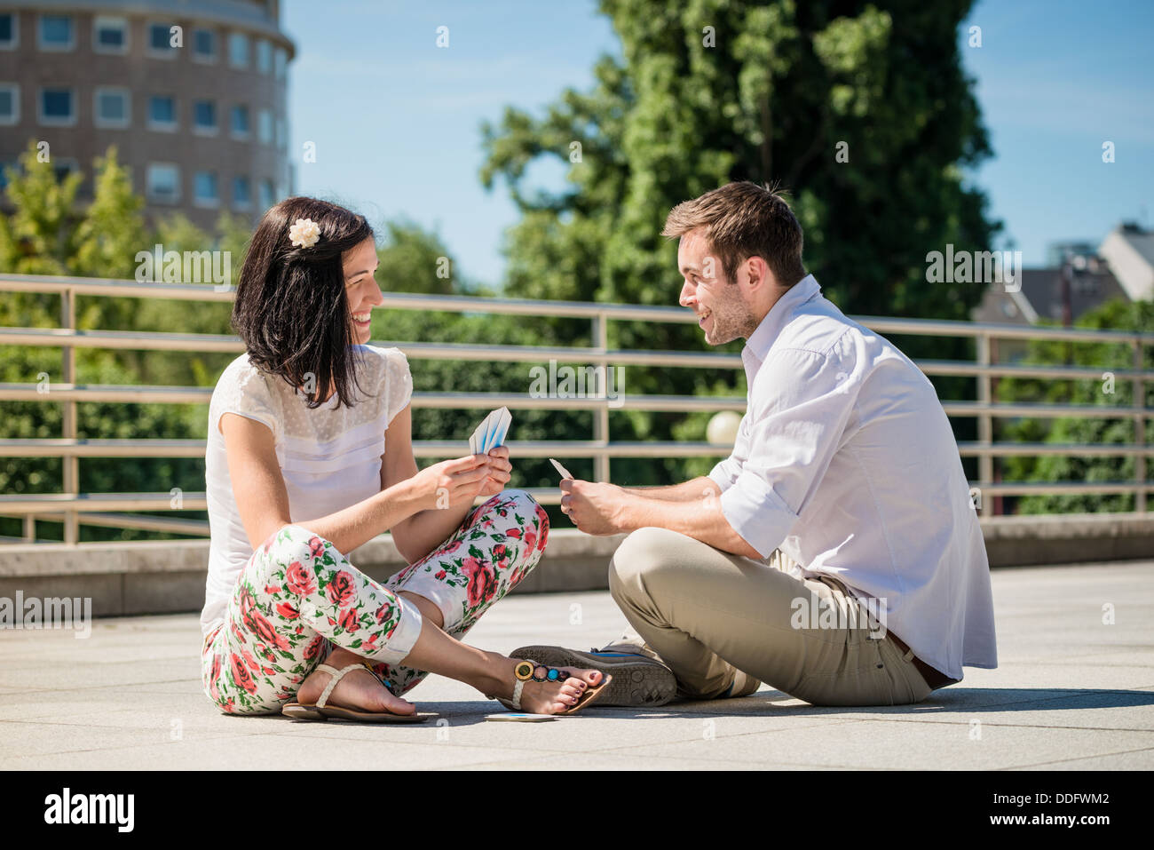 Young couple playing cards outdoor sitting on ground Stock Photo - Alamy