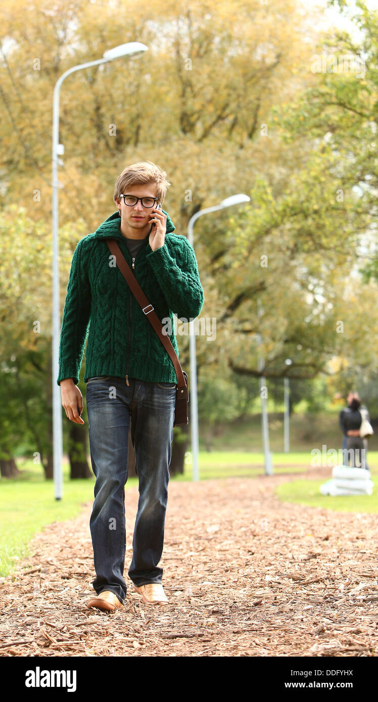Handsome guy walking with cellphone in the park Stock Photo - Alamy
