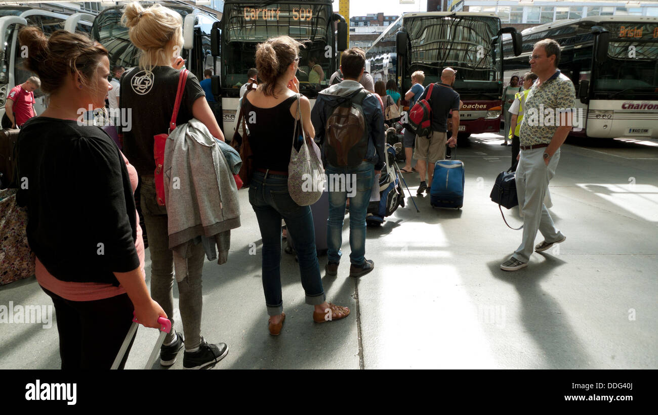 Rear view of queue passengers queuing for a National Express bus to ...