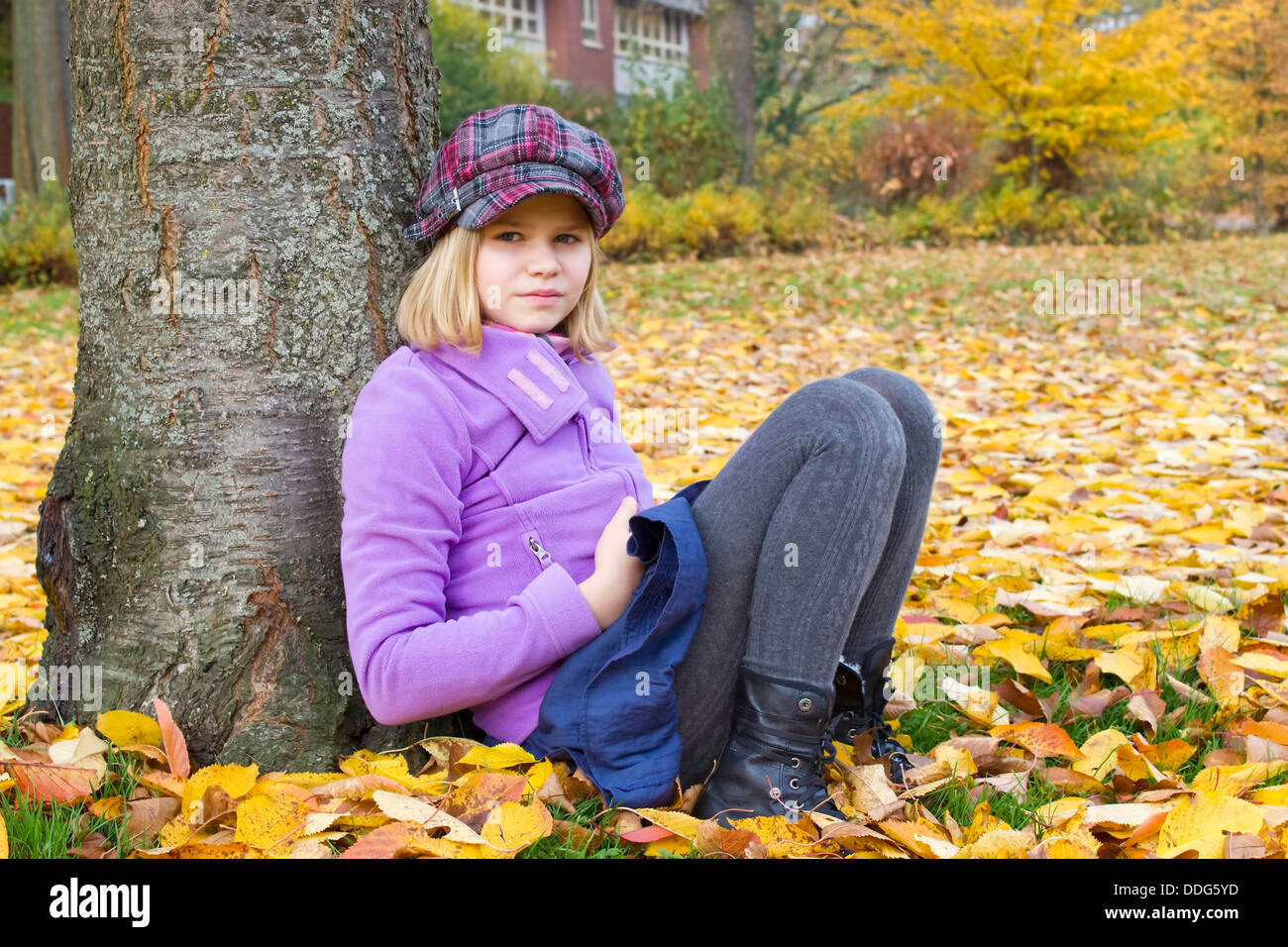 Full length portrait of a little girl sitting under tree in autu Stock ...