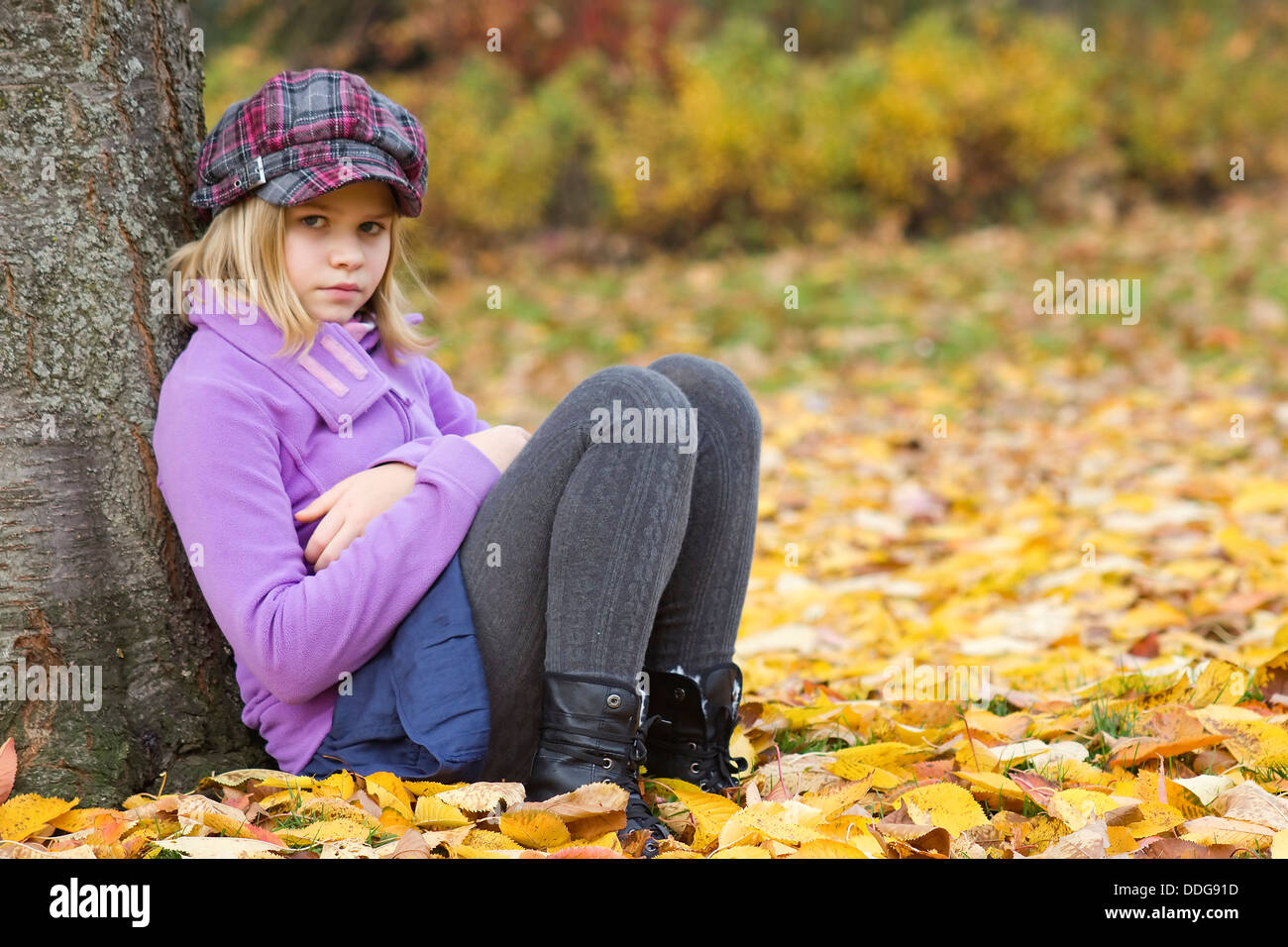 Full length portrait of a little girl sitting under tree in autu Stock ...