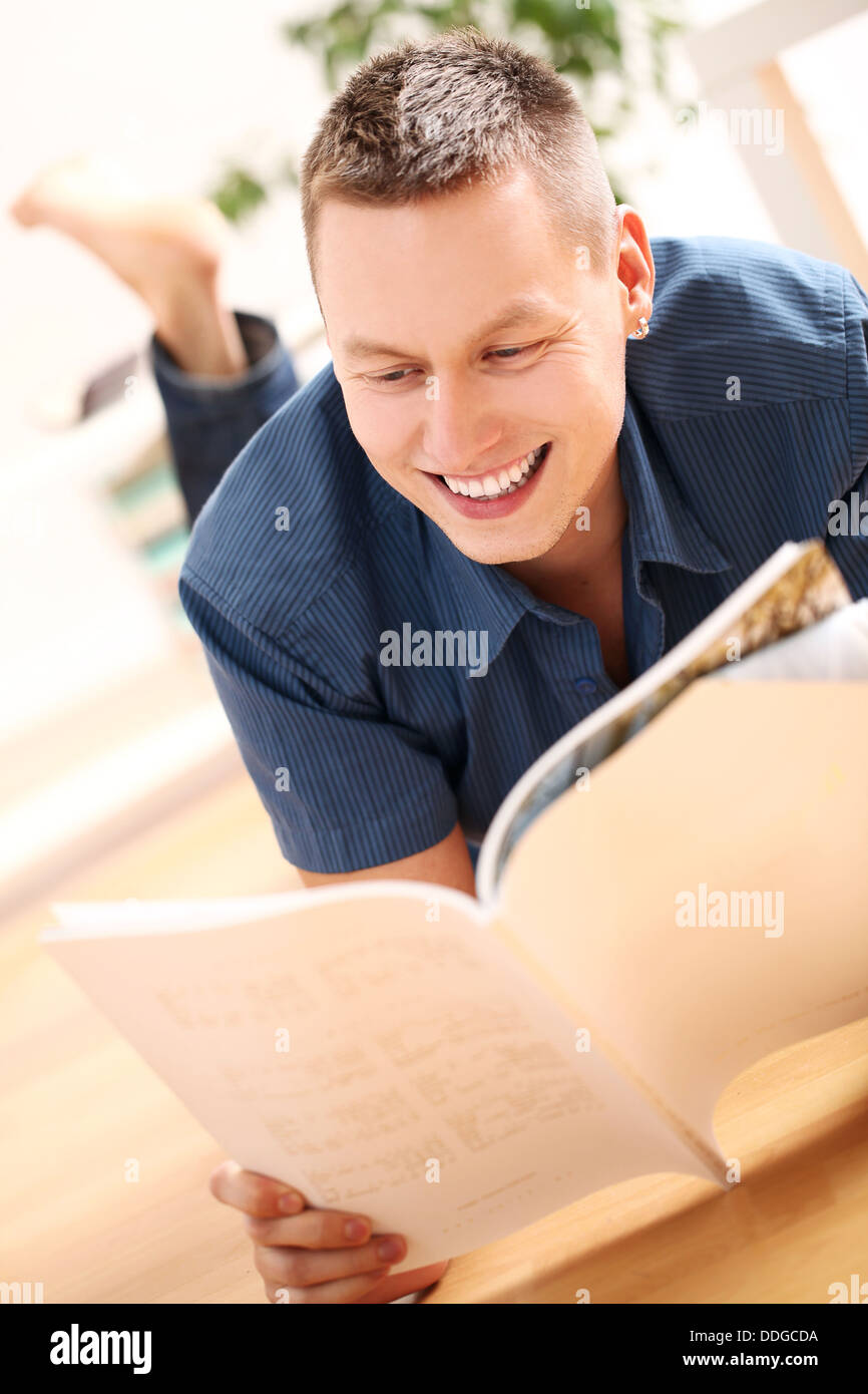 Young man reading magazine at home Stock Photo - Alamy