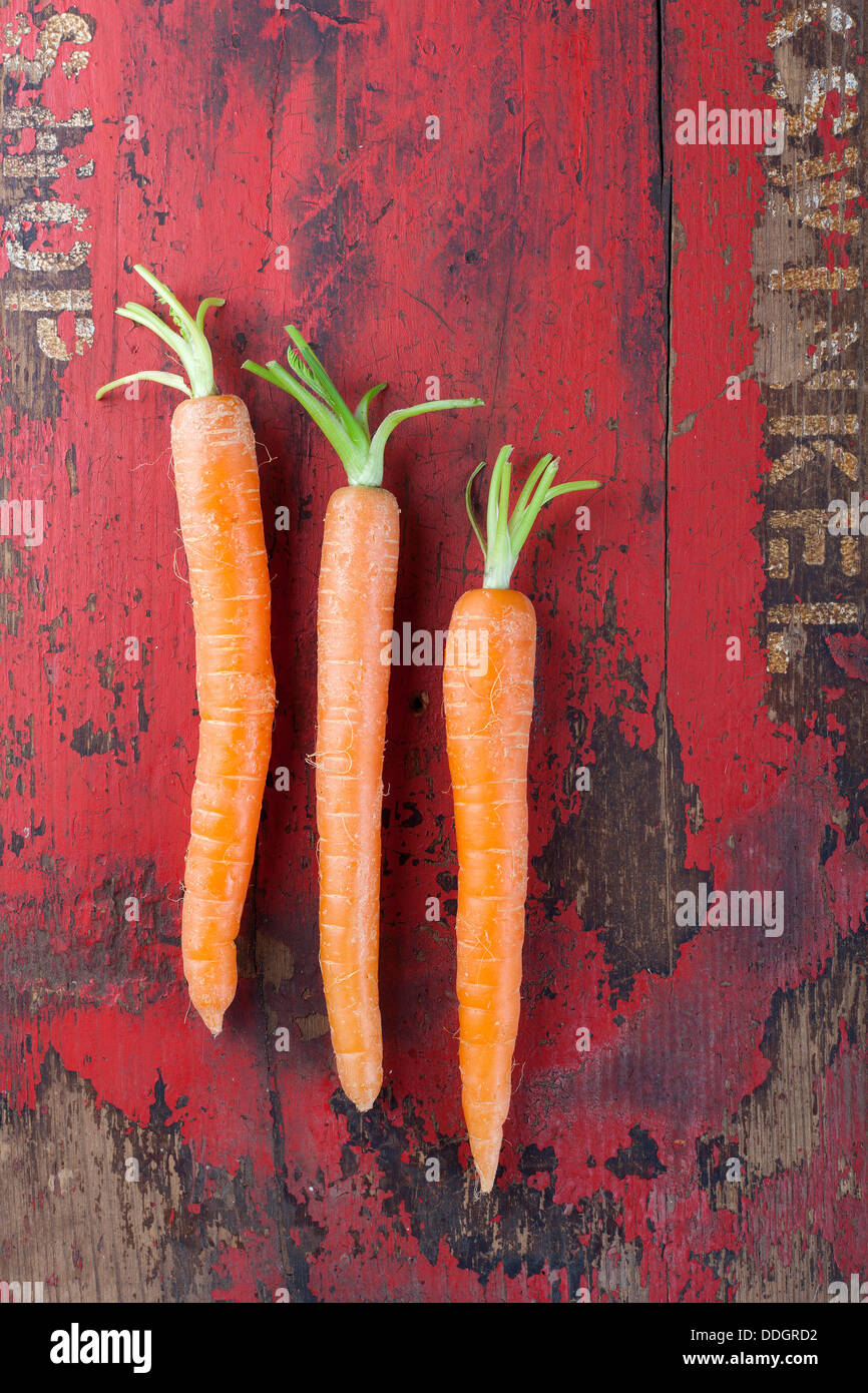 Three carrots placed on a textured red surface Stock Photo - Alamy