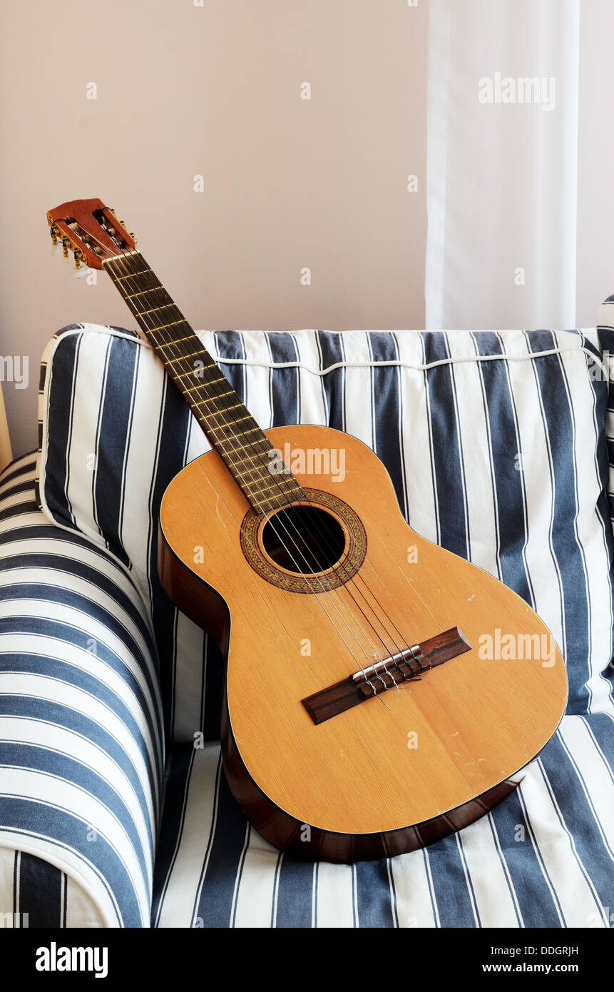 acoustic guitar on a striped couch, vertical Stock Photo - Alamy