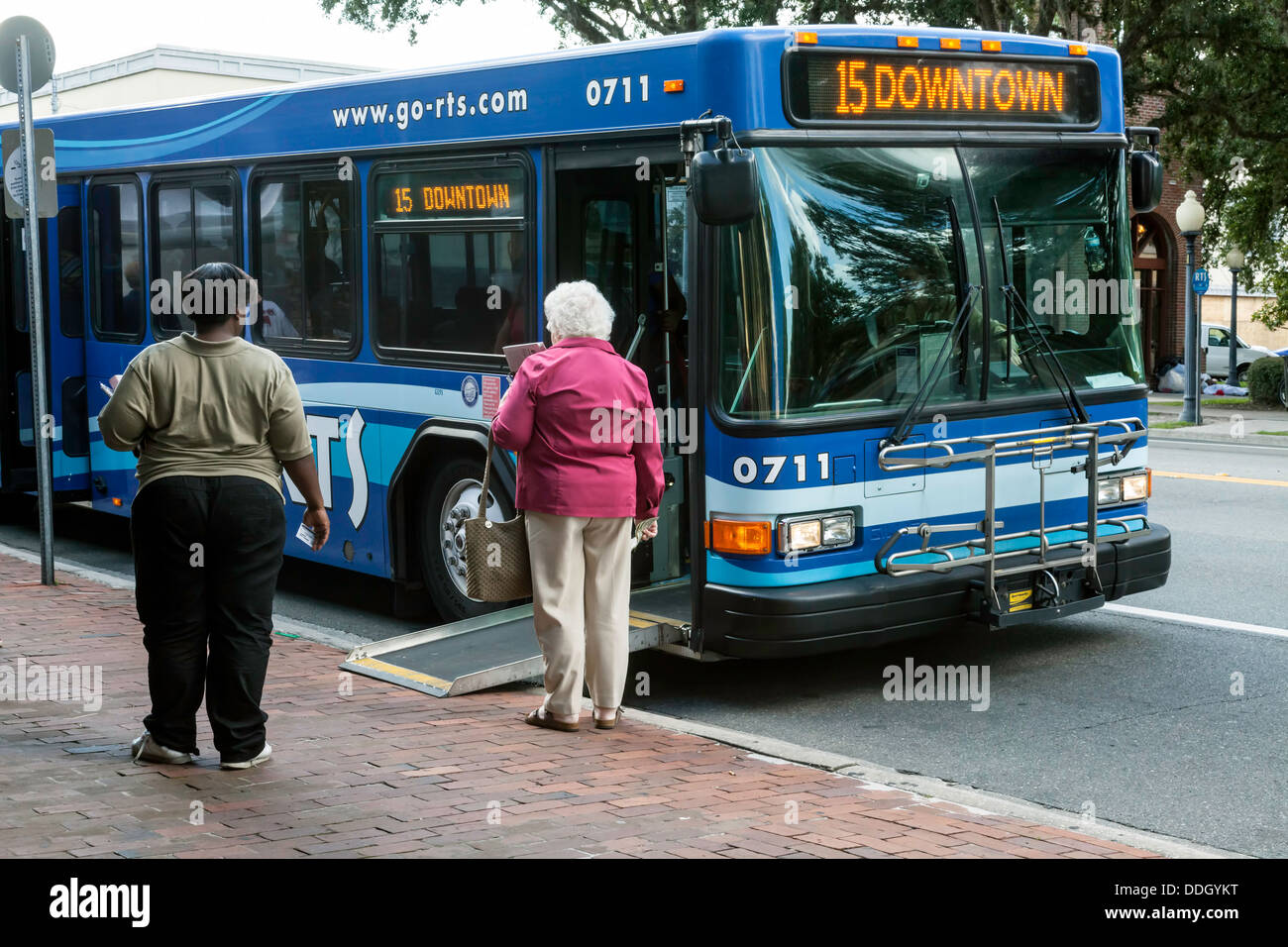 Public city bus deploys its wheelchair ramp while women wait at the Bo ...