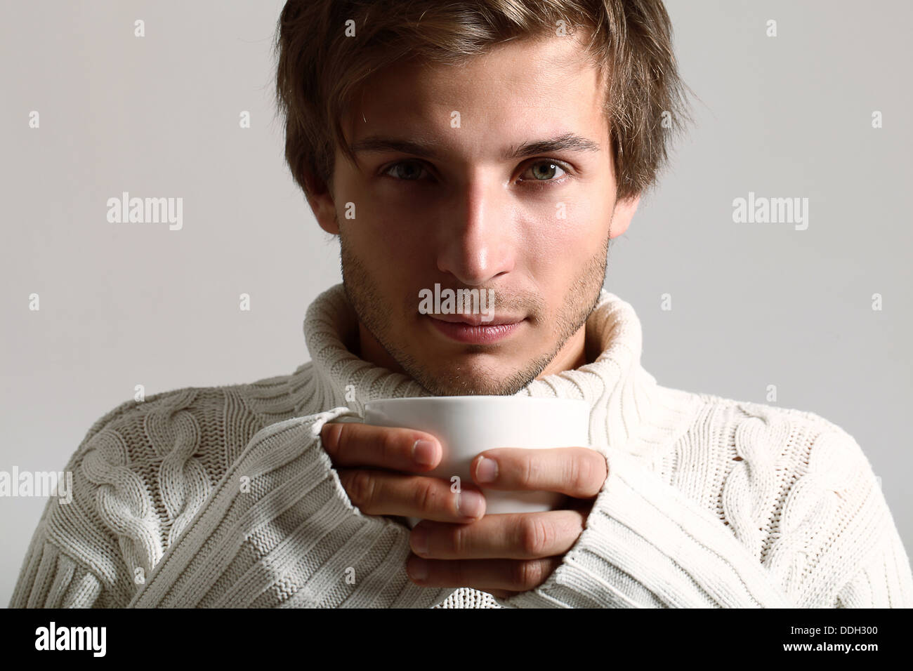 Handsome man in sweater drinking tea Stock Photo - Alamy