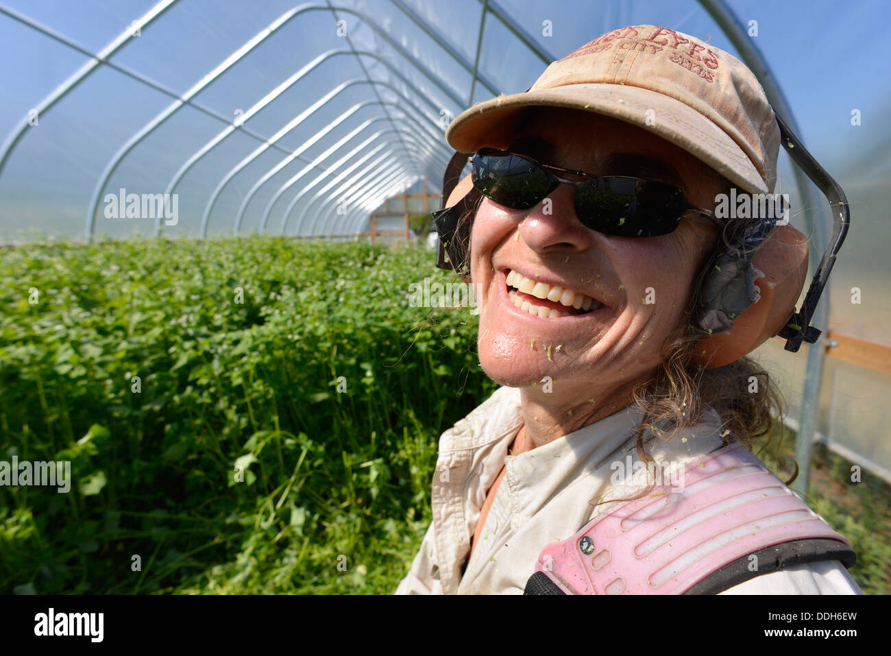 Woman with plant debris on her face after weed-whacking cover crop in a ...