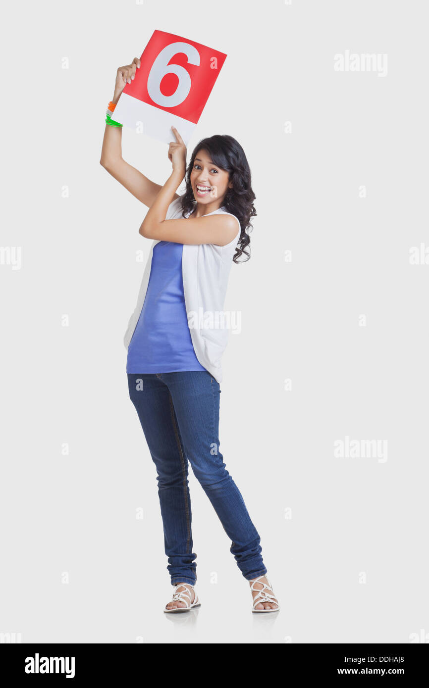 Full length portrait of happy young woman pointing at number 6 over ...
