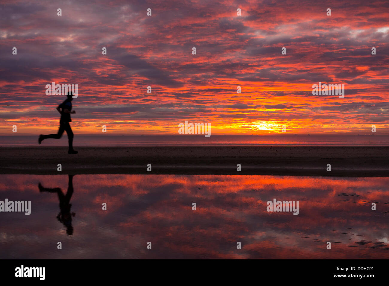 Man jogging on beach against dramatic sunrise. Seaton Carew near ...