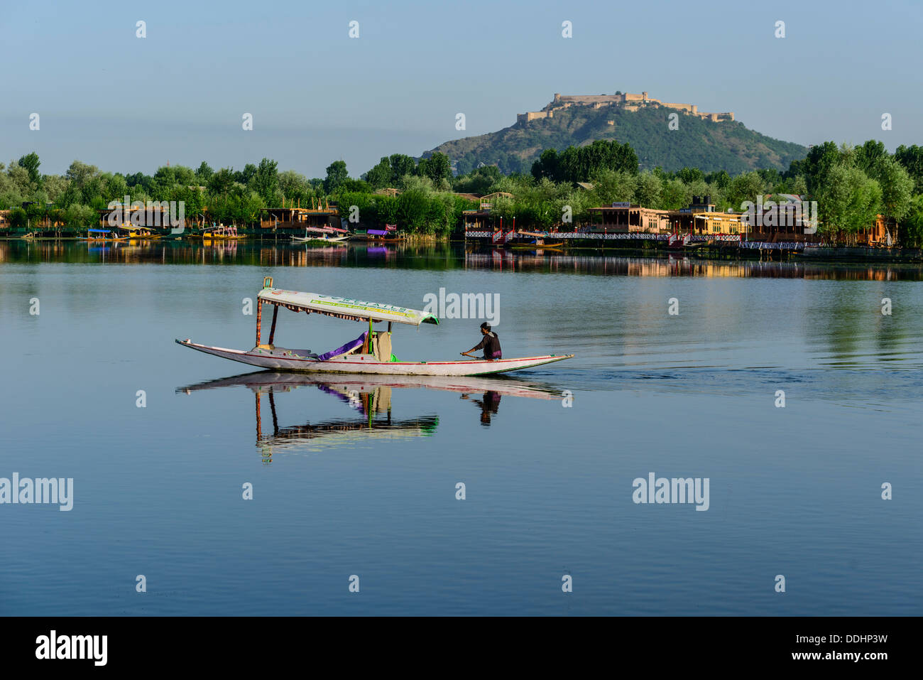 A shikara boat crossing Dal Lake, houseboats and the Durrani Fort on ...
