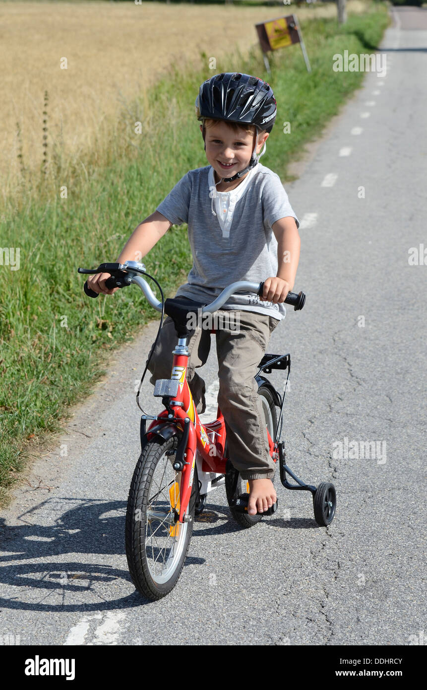 Boy riding a bicycle with training wheels Stock Photo - Alamy