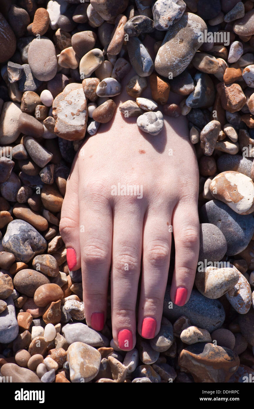Girls hand buried in pebbles Stock Photo - Alamy