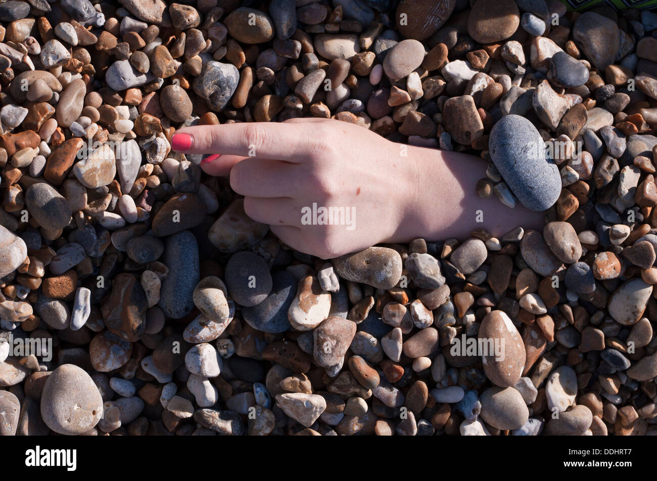 Girls hand buried in pebbles Stock Photo - Alamy