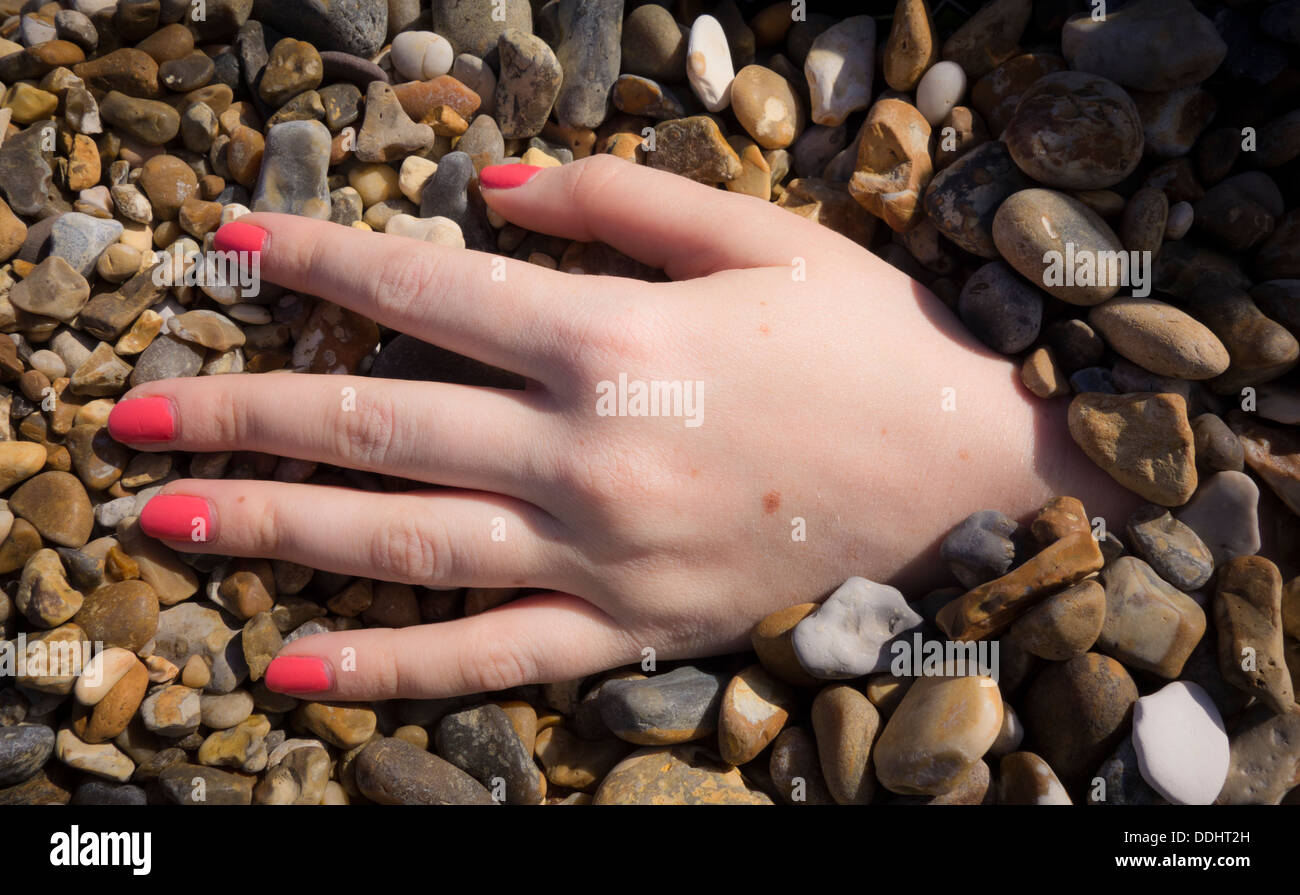 Girls hand buried in pebbles Stock Photo - Alamy