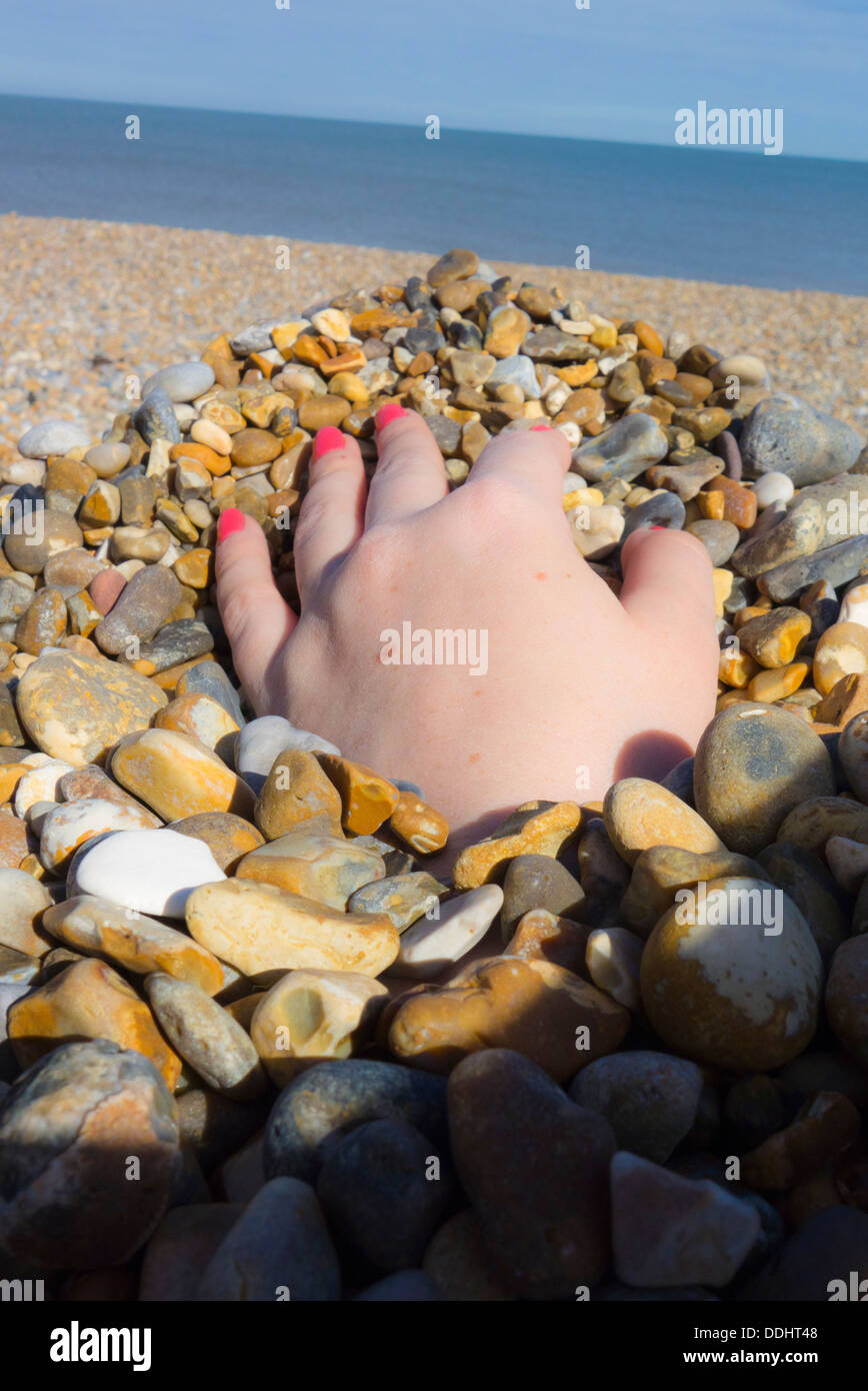 Girls hand buried in pebbles Stock Photo - Alamy
