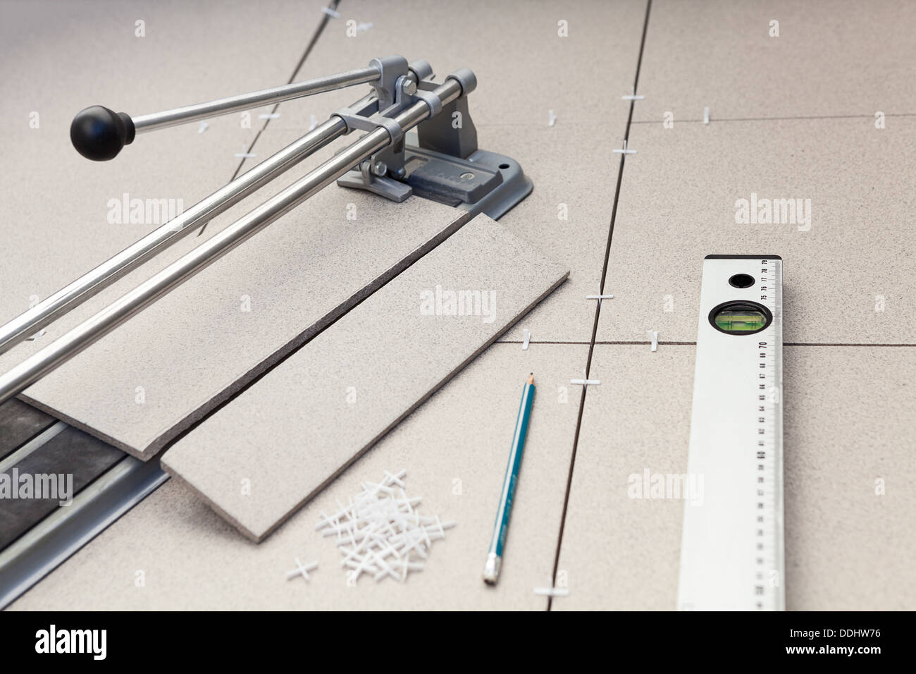 Small tile-cutter with laying tiles, pencil and level tube on floor ...
