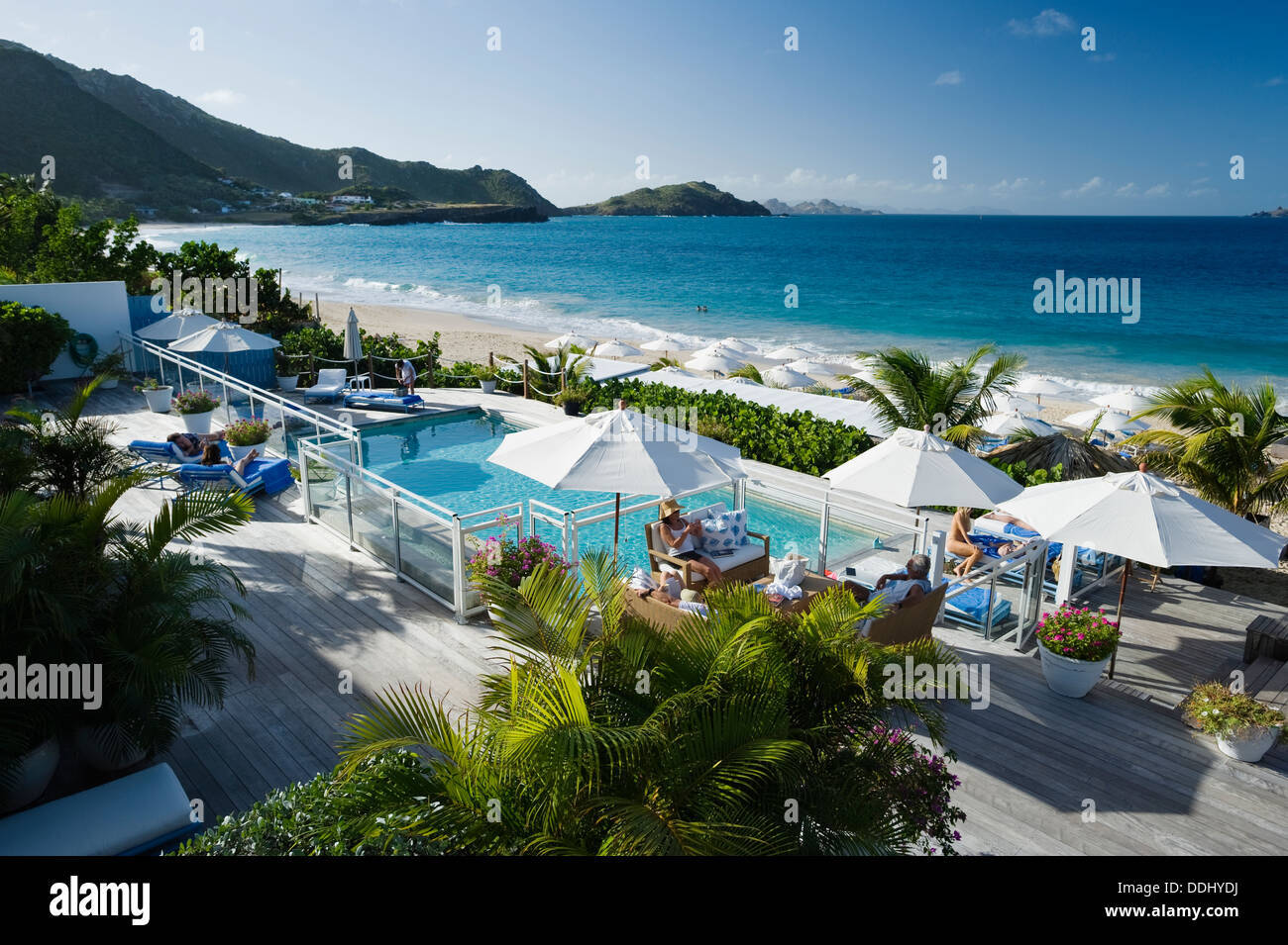 Wooden decking area with swimming pool. parasols and beach view Stock ...