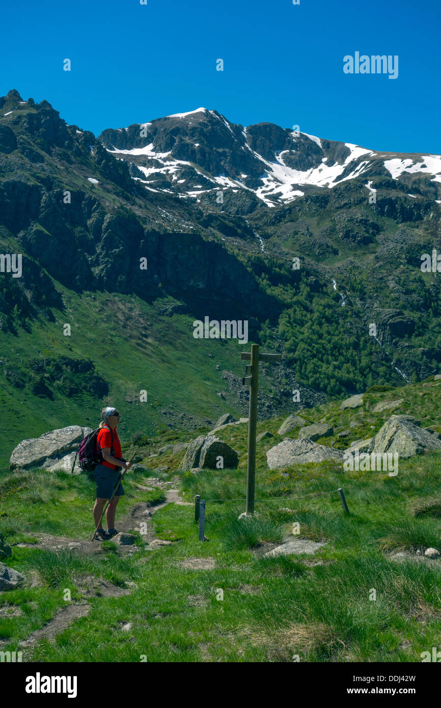 Female figure in red walking hiking in French Pyrenees with signpost ...
