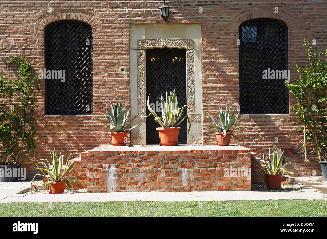 Carved marble door in a red bricks wall with agave plants Stock Photo ...