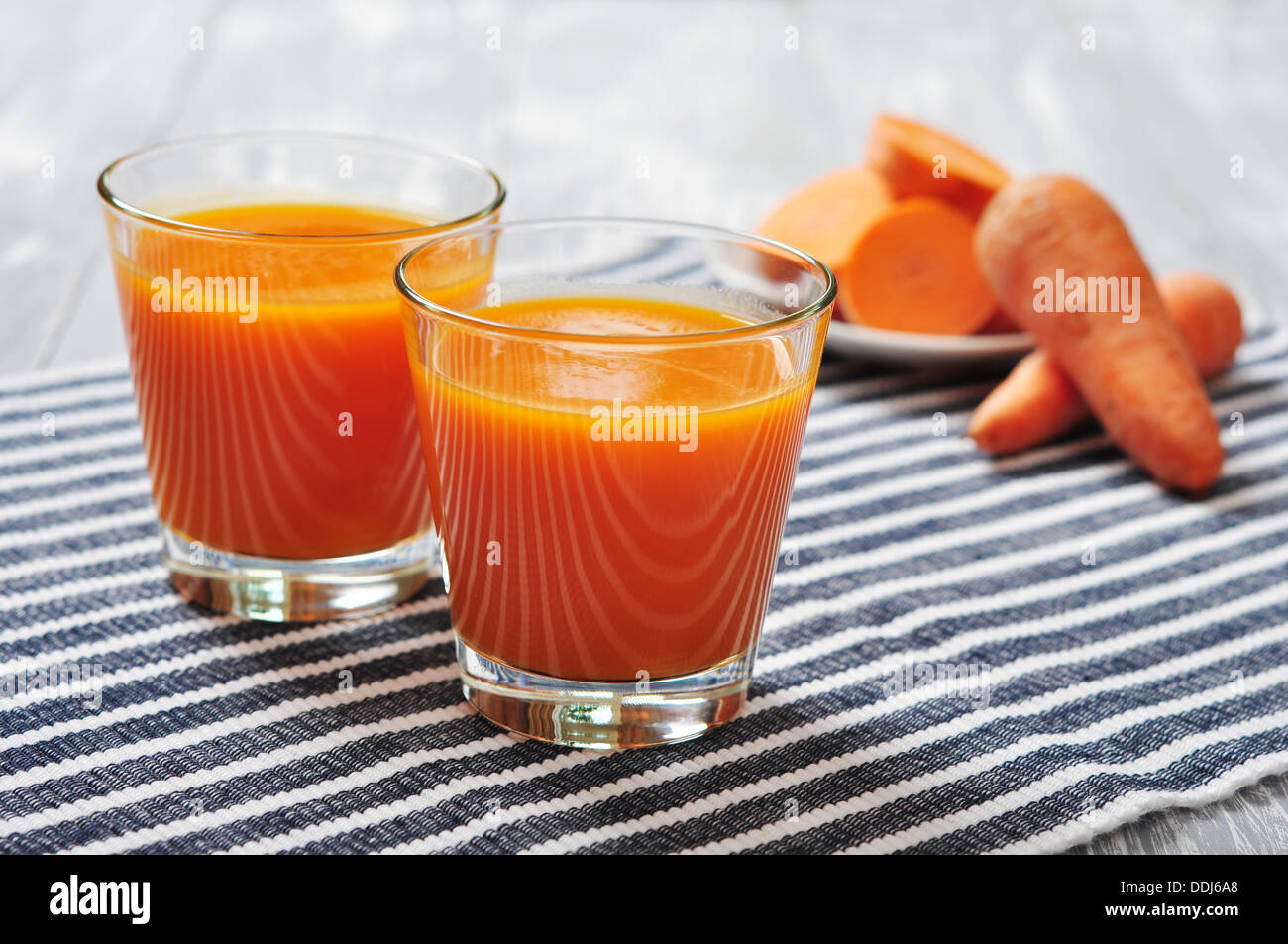 glasses of carrot juice and fresh carrots on wooden background Stock ...